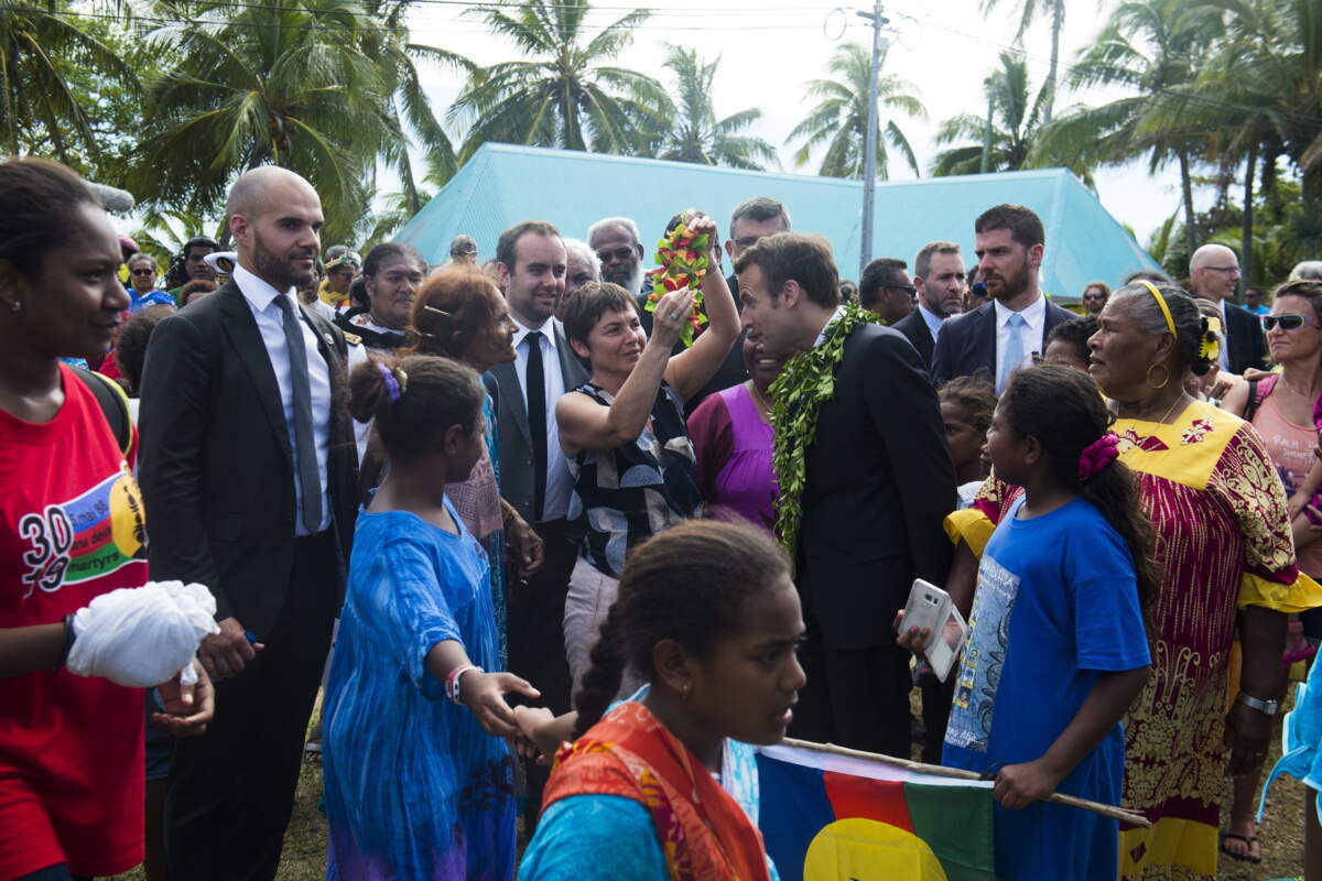 Emmanuel Macron pose avec une couronne de fleurs sur la tête, en visite ...
