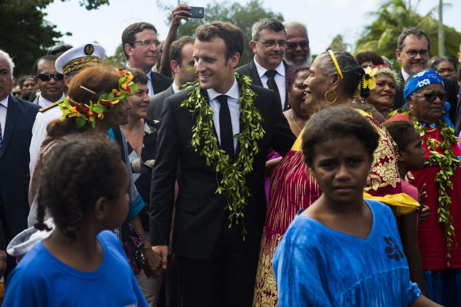 Emmanuel Macron pose avec une couronne de fleurs sur la tête, en visite ...